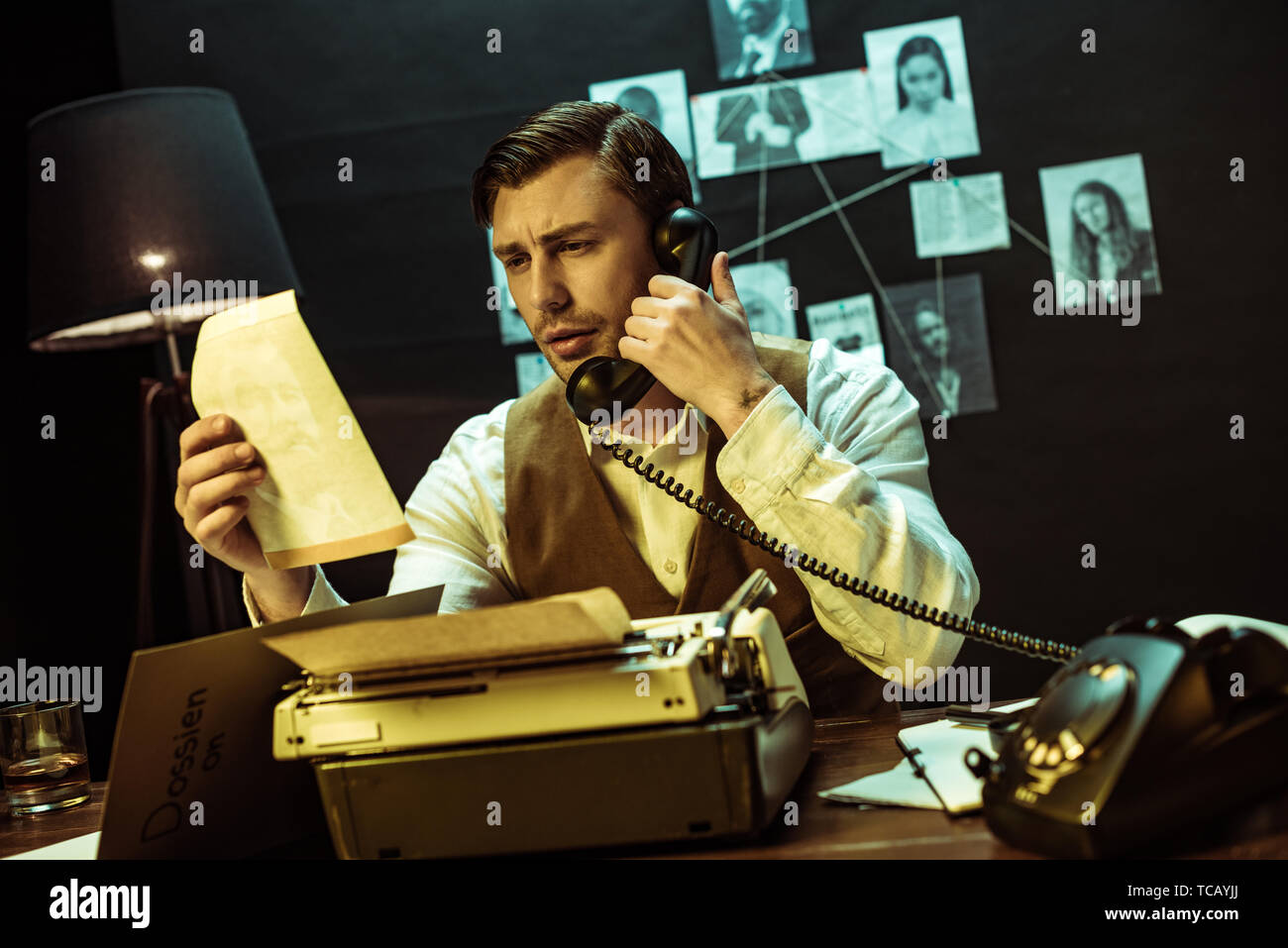 Detective reading document while talking on telephone in office Stock ...