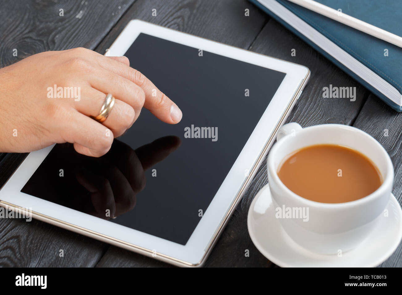 hands of a man holding blank tablet device over a wooden workspace ...