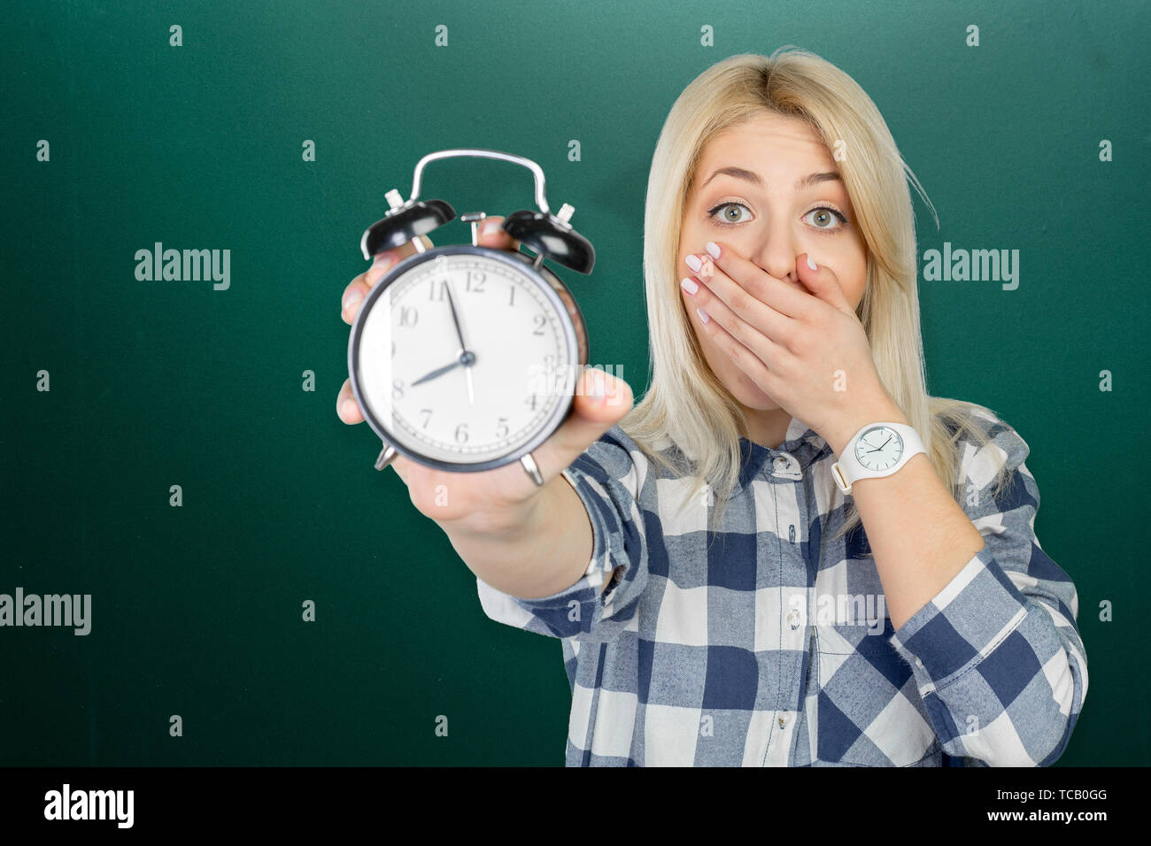Girl showing clock over black board background Stock Photo - Alamy