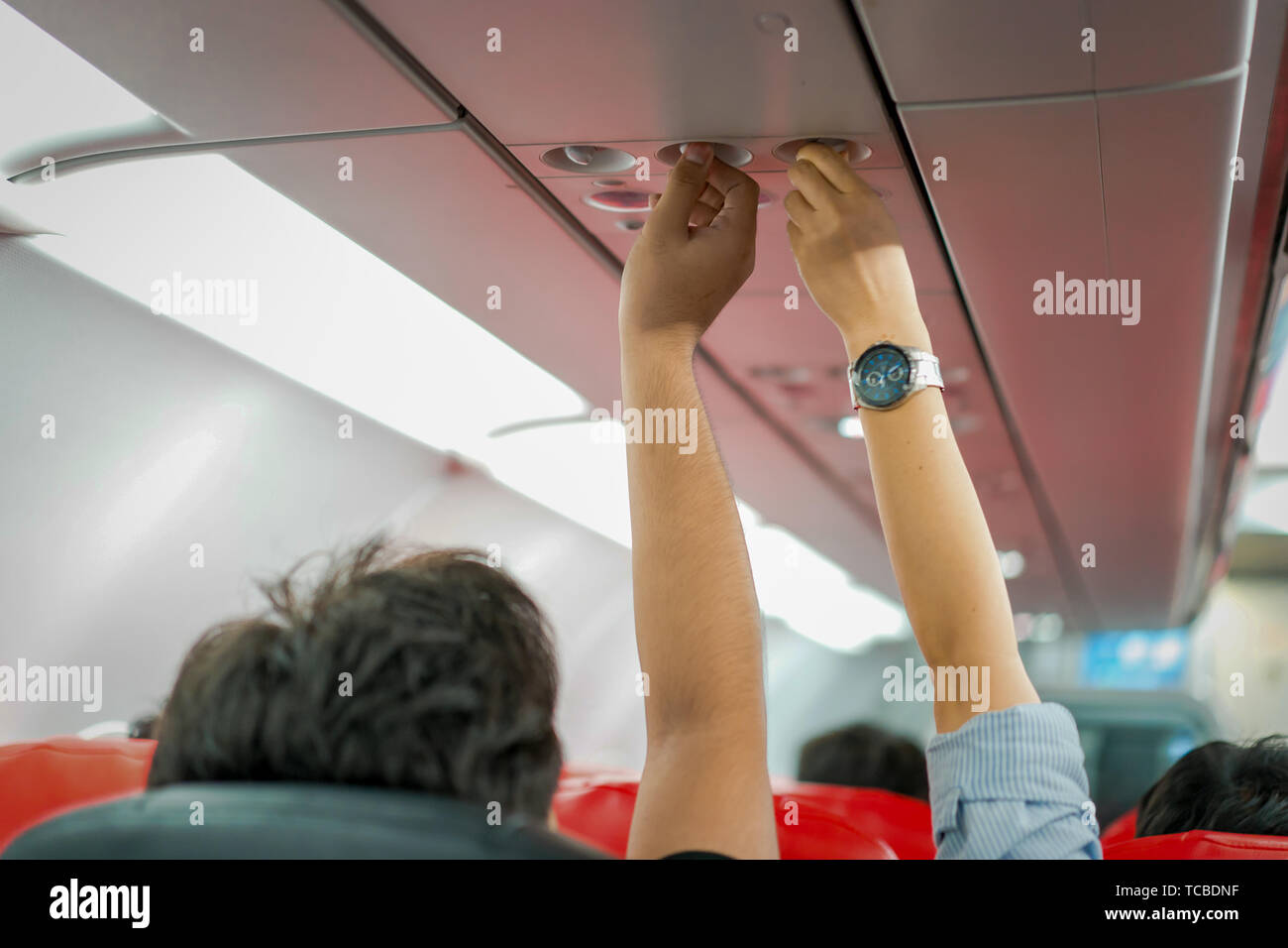 Asian couple people cabin crew, hand up to adjust console panel; the ...