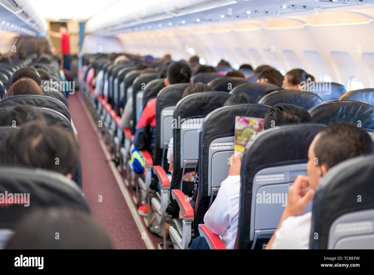 Asian passenger reading the magazine / menue / catalog while waiting ...