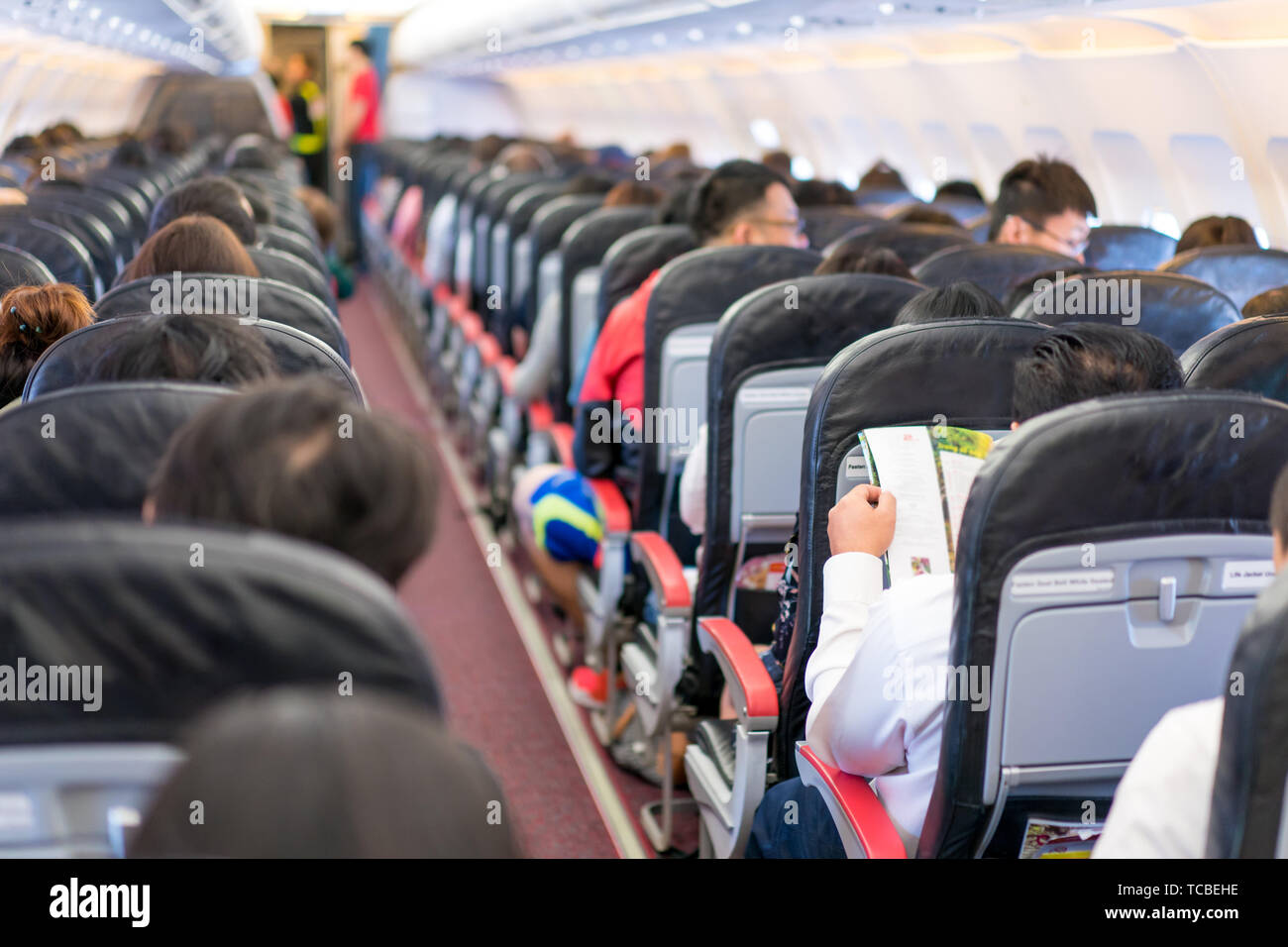 Asian passenger reading the magazine / menue / catalog while waiting ...