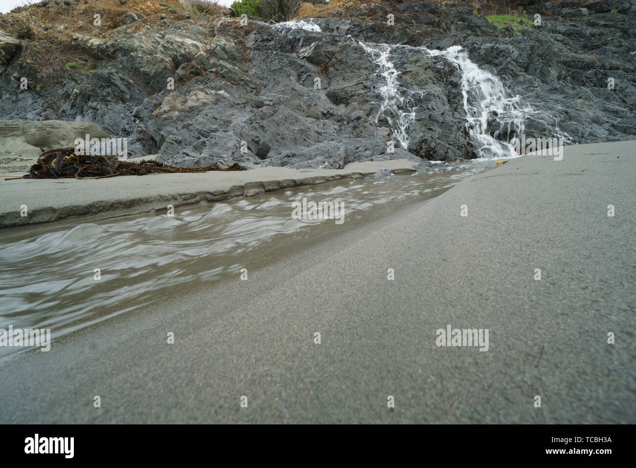 Natural waterfall over cliffs to sand beach Stock Photo - Alamy