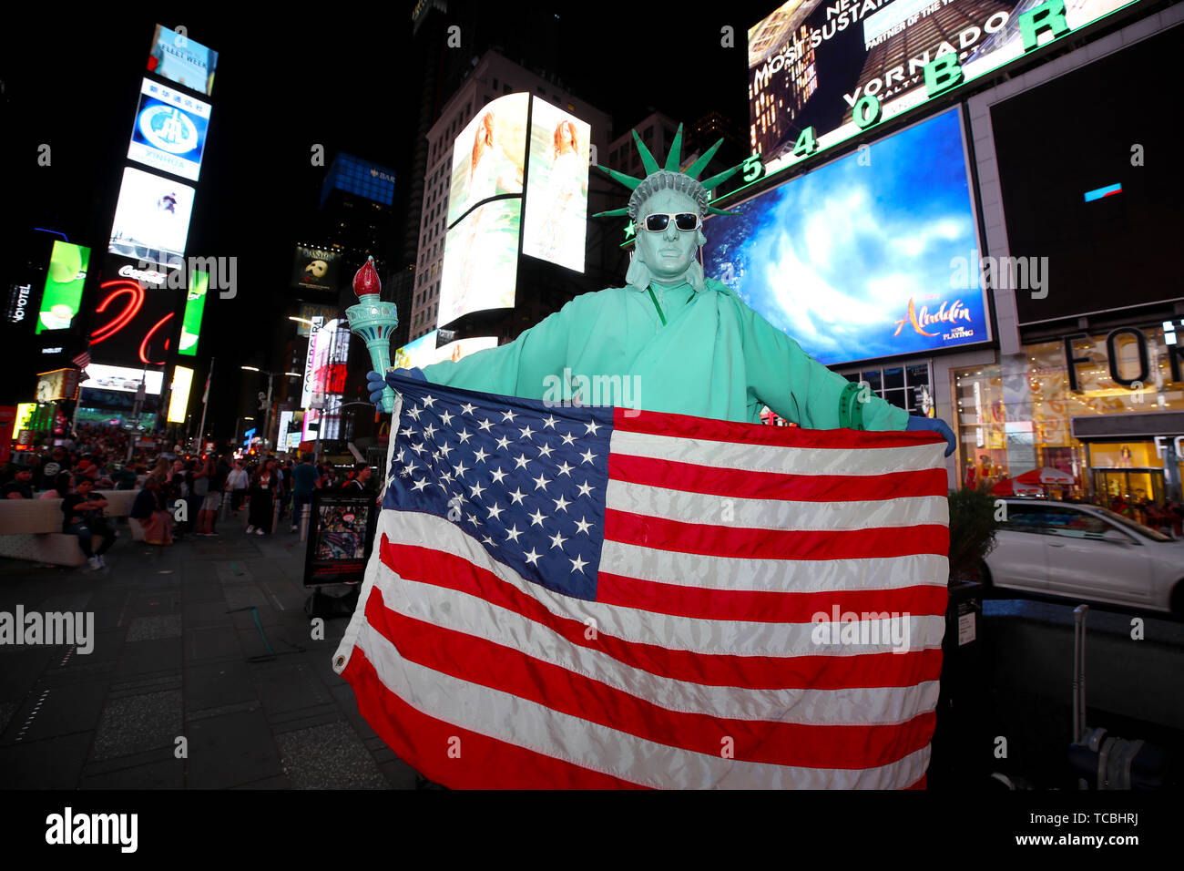 A man dressed as the Statue of Liberty hold a US flag in Times Square ...