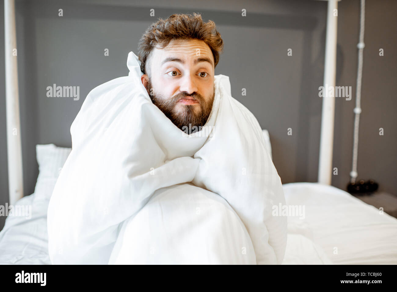 Frustrated man with emotional insanity sitting on the bed covered with ...