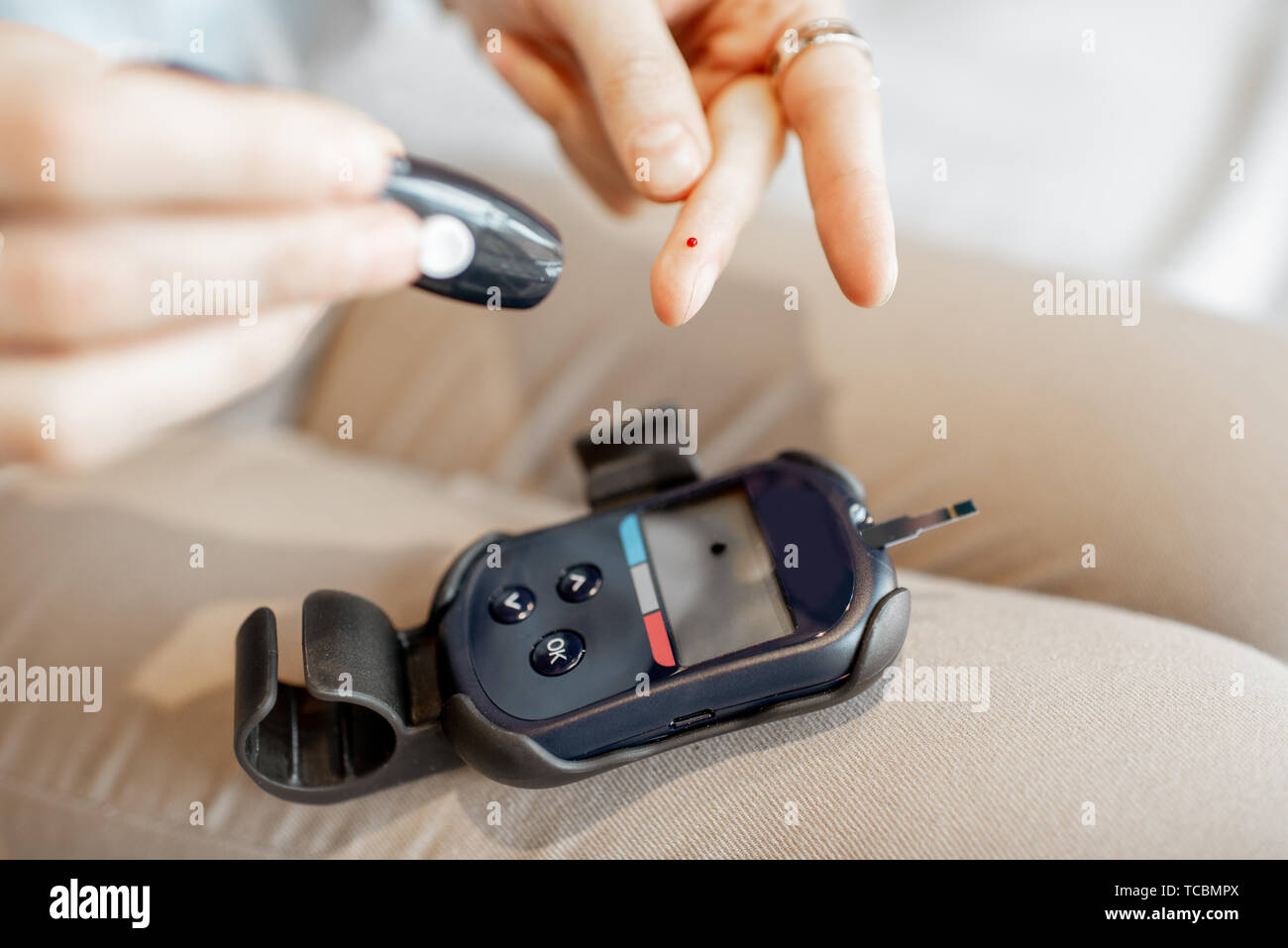 Young woman measuring the level of blood glucose using portable ...