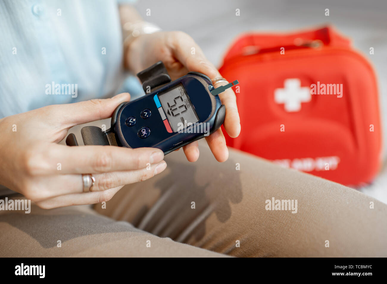 Young woman measuring the level of blood glucose using portable ...