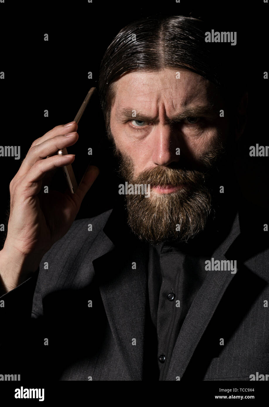 Old believer senior priest with a smartphone, bearded old man is ...