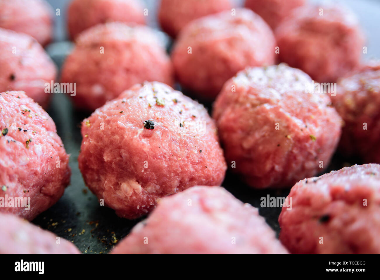 Raw uncooked turkey meatballs on tray. Fresh minced meat, pepper, salt ...