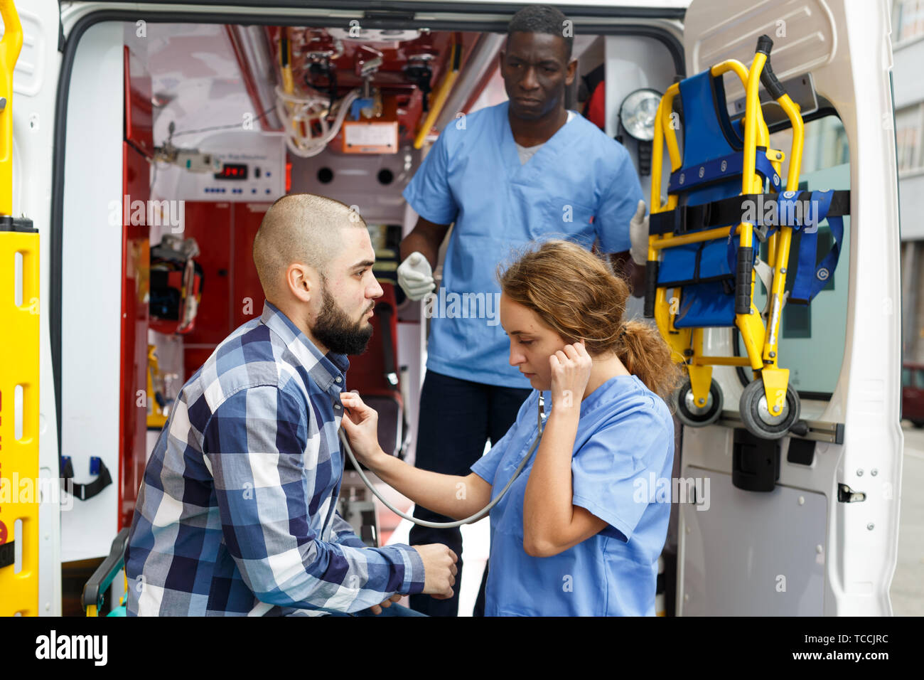 Ambulance team providing medical care to patient on stretcher in ...
