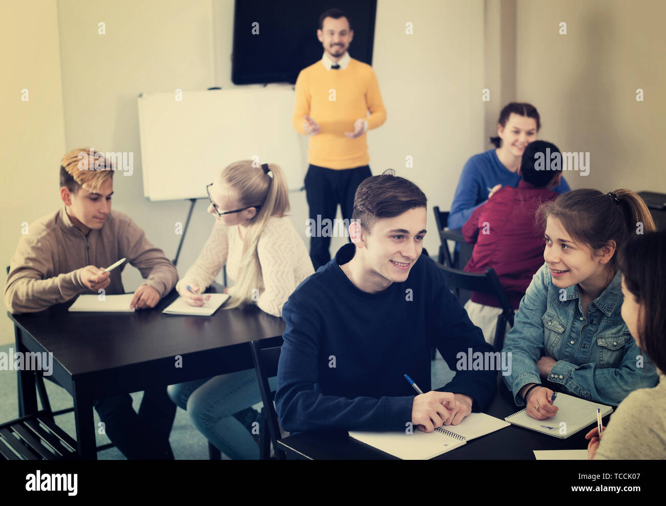 Happy classmates and teacher working in groups to complete task during ...