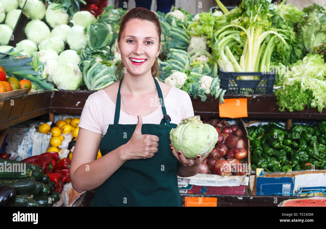 Portrait of seller woman who is holding cabbage in the grocery Stock ...