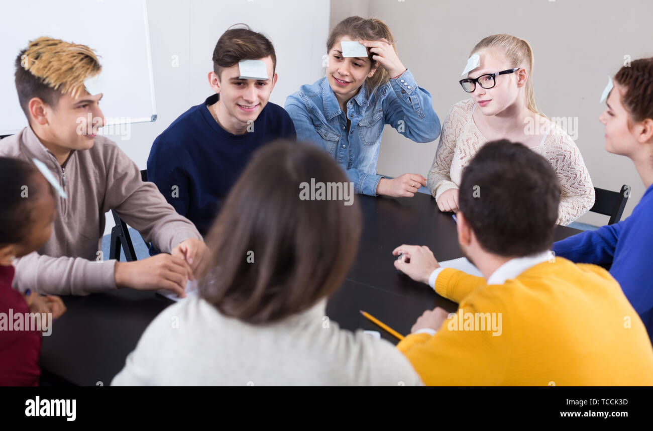 positive spanish classmates having round of guess-who game during class ...