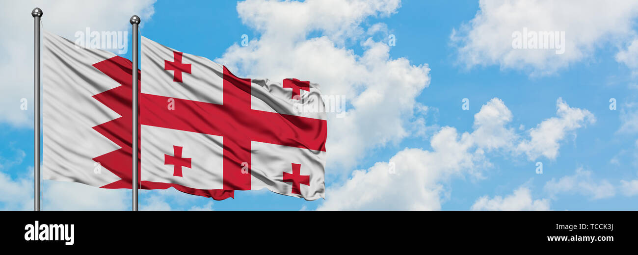 Bahrain and Georgia flag waving in the wind against white cloudy blue ...