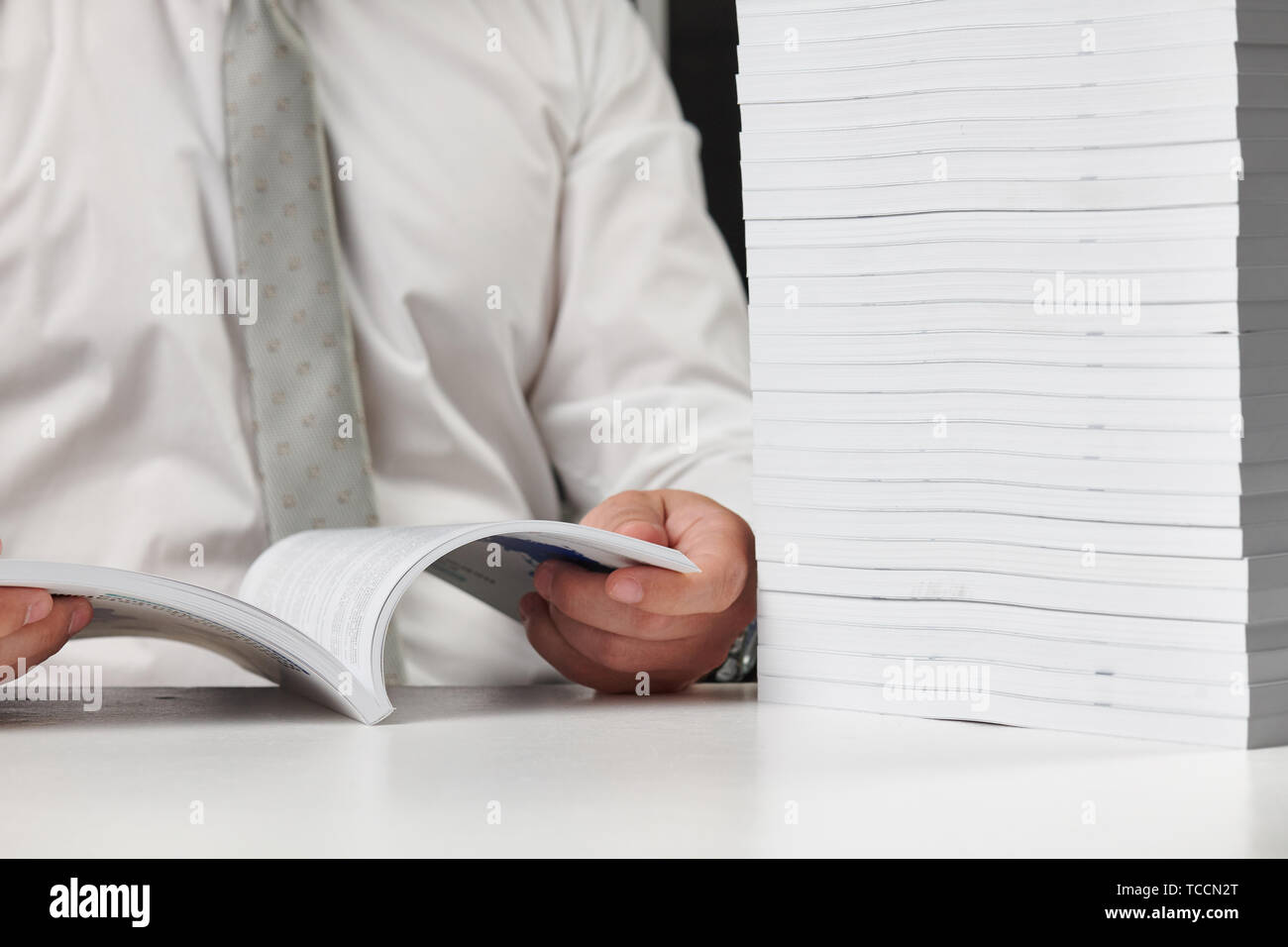 Businessman working at an office, reads stack of books and reports ...