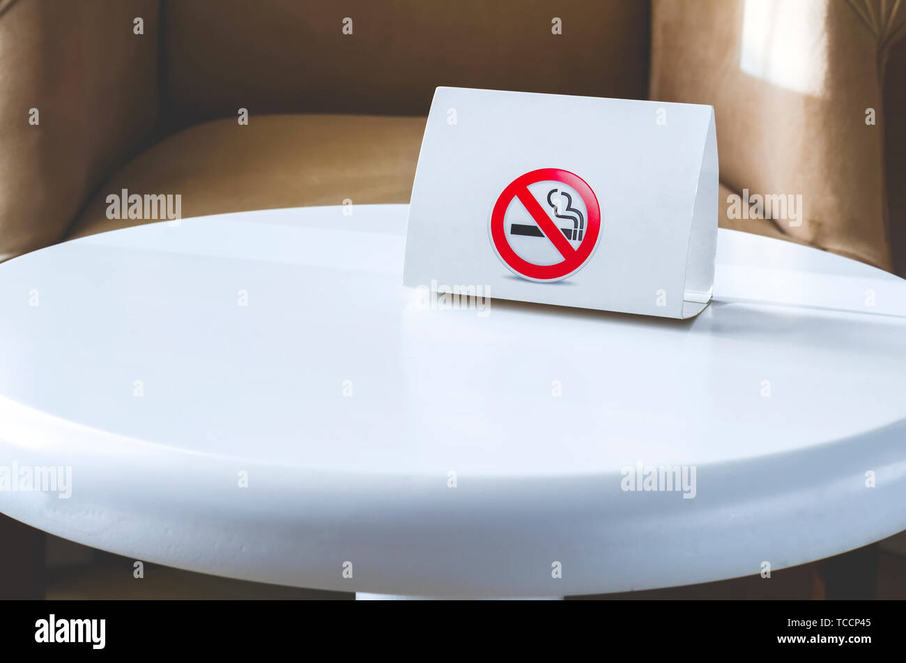 White cardboard sign No smoking on a white round table. Hotel indoor ...