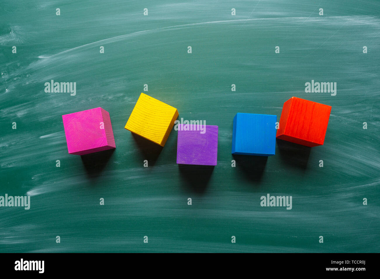 colored wooden cubes on green chalkboard Stock Photo - Alamy