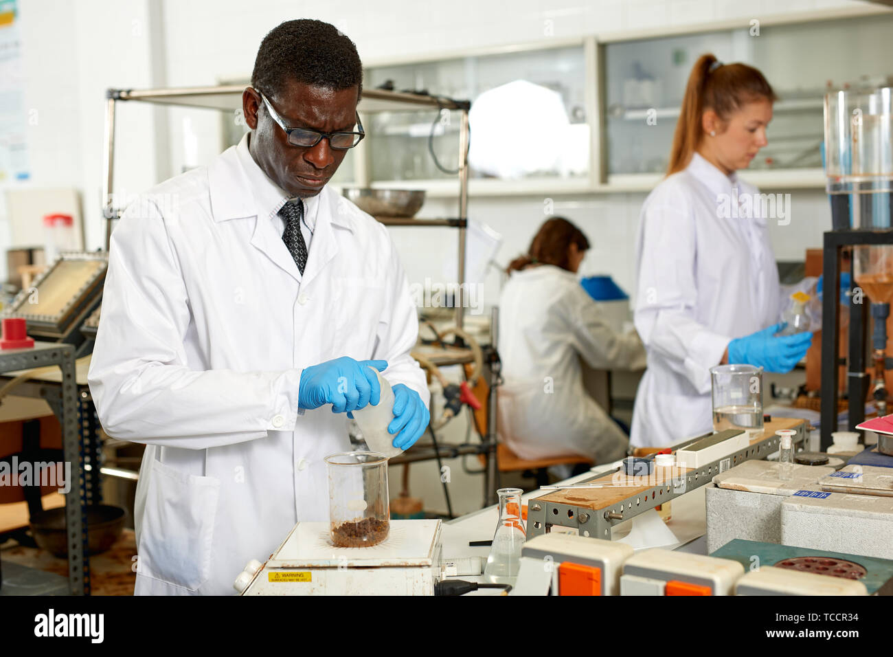 Focused male lab scientist in glasses working with different reagents ...