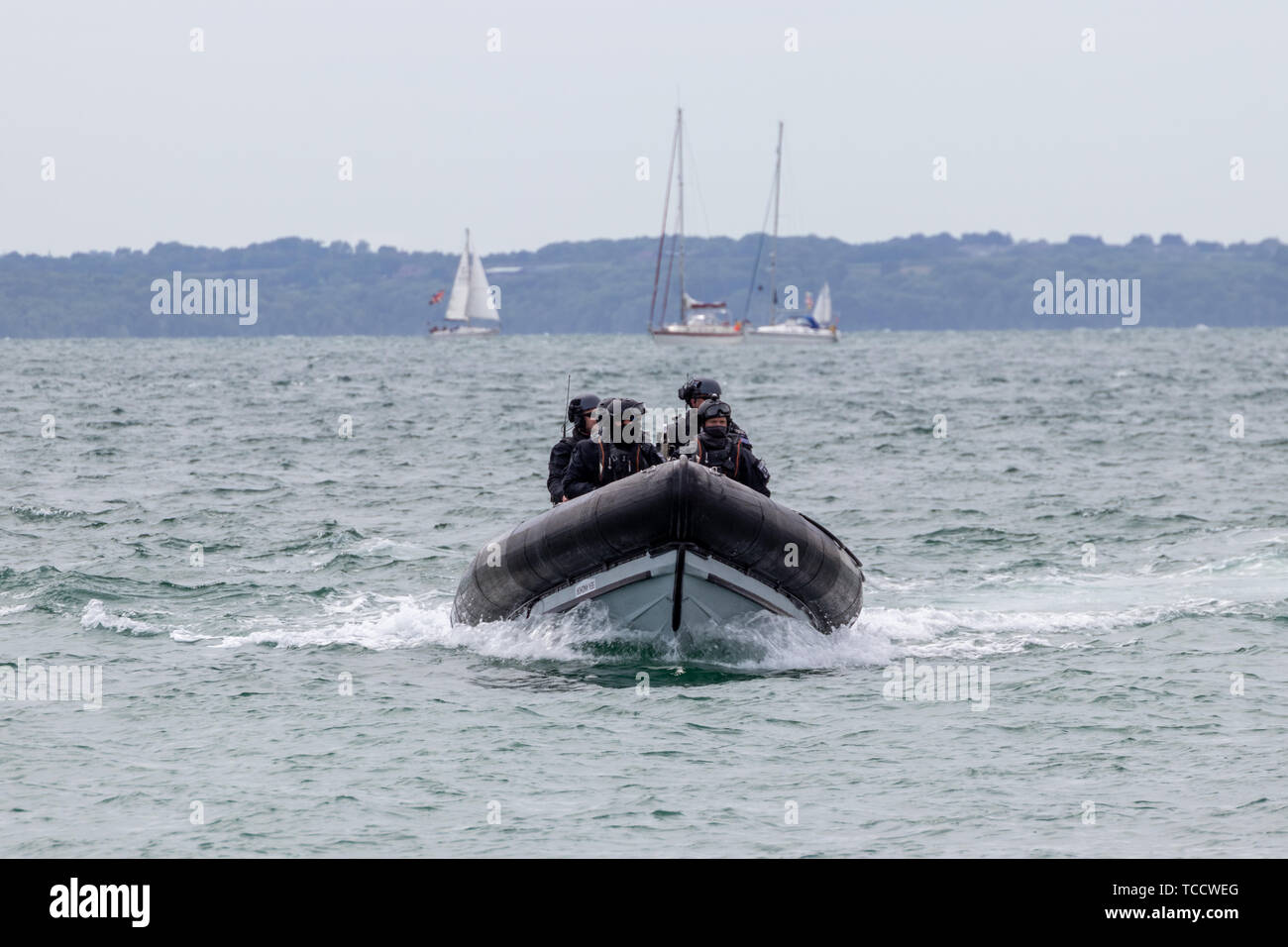 Masked British police officers on a rigid inflatable boat patrolling ...