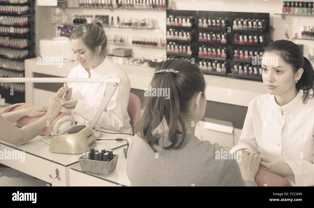 nail technicians performing manicure procedure behind the workplace in ...