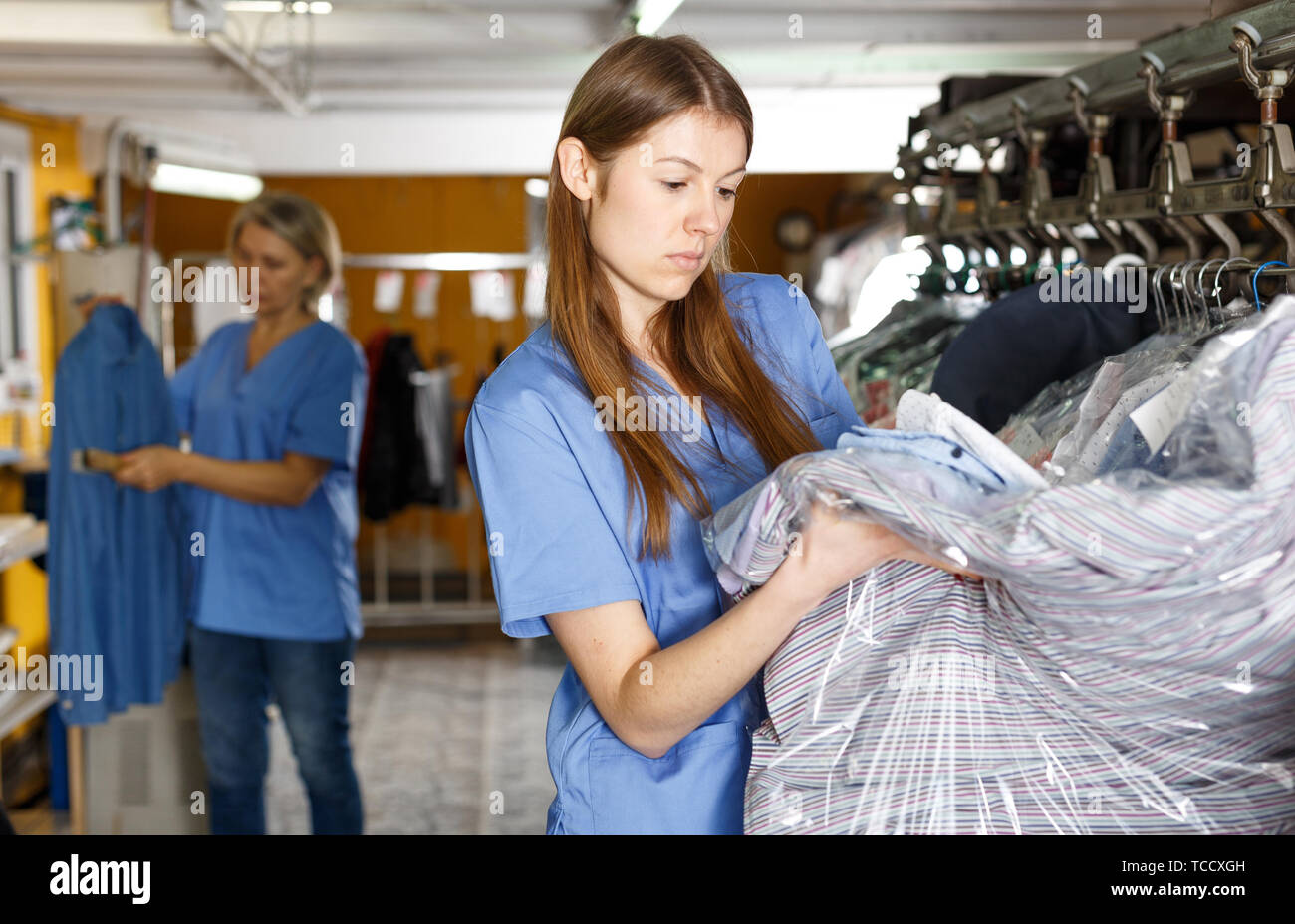 Two female dry-cleaning salon employees in process of work Stock Photo ...