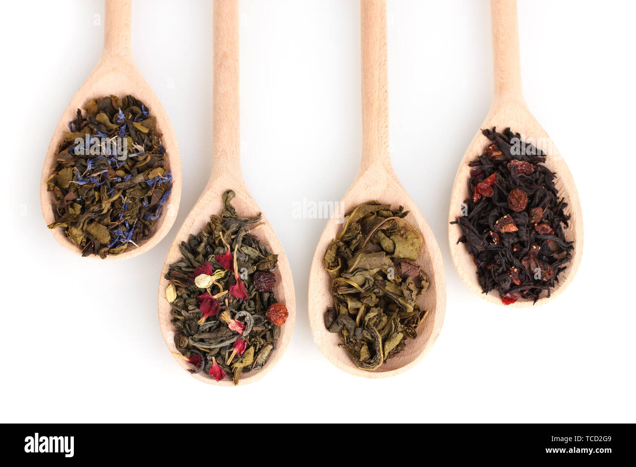 Different dry green and black tea in wooden spoons isolated on white ...