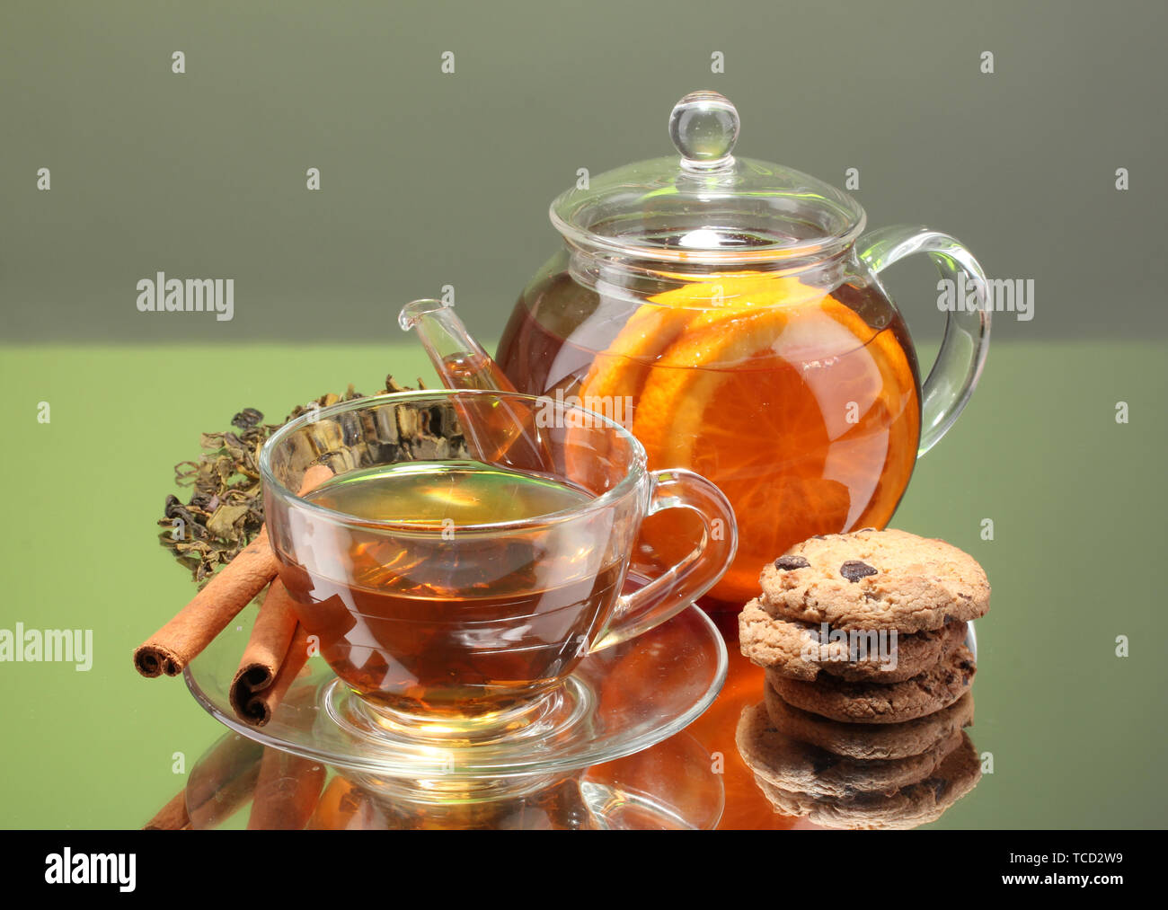 Black exotic fruit tea in glass teapot and cup on green background ...