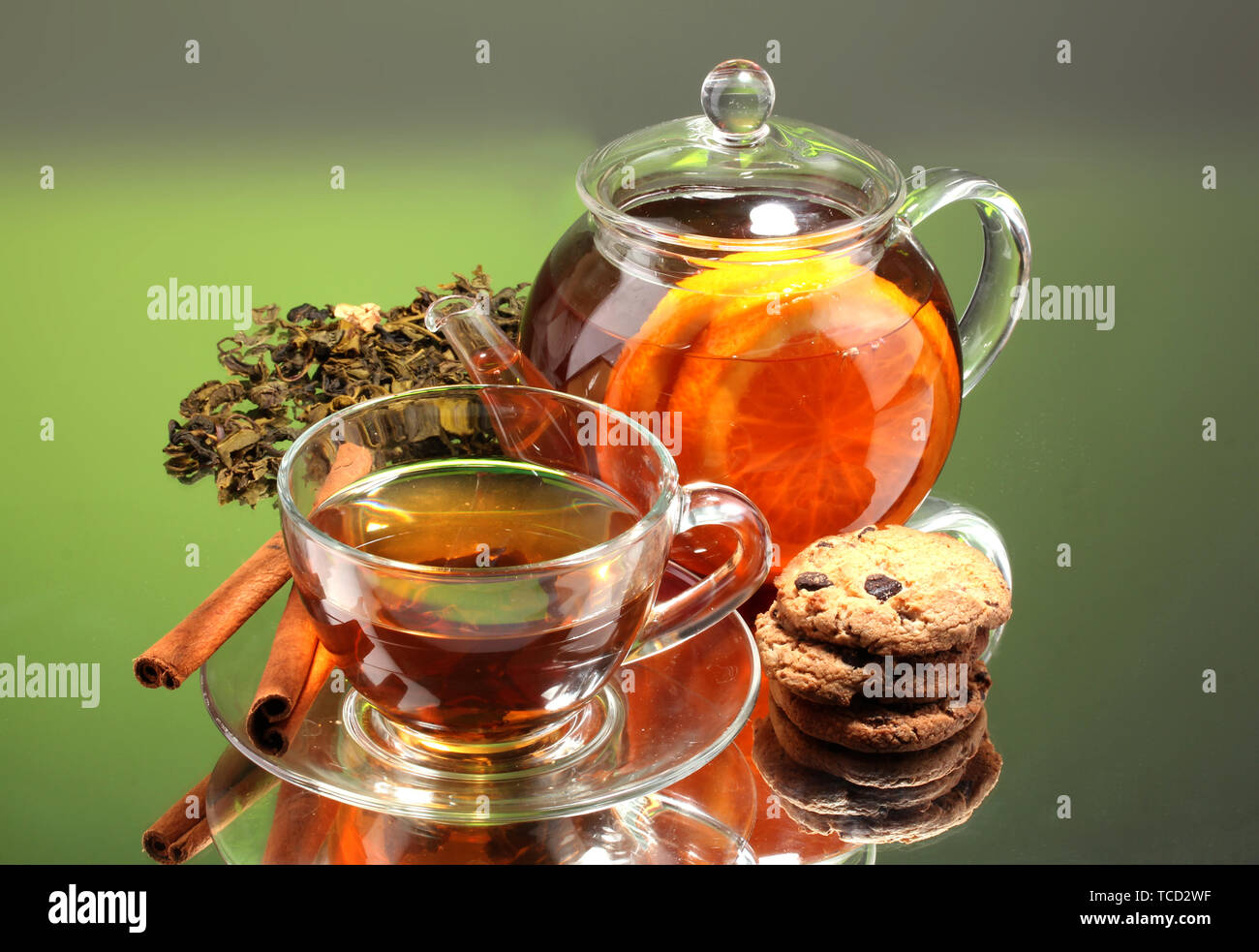 Black exotic fruit tea in glass teapot and cup on green background ...