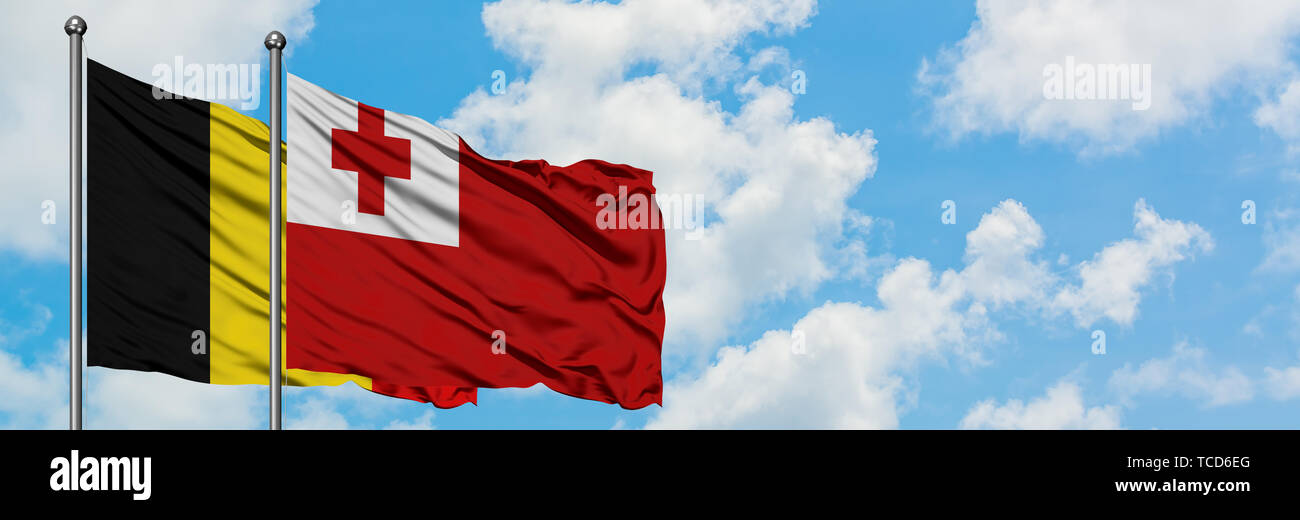 Belgium and Tonga flag waving in the wind against white cloudy blue sky together. Diplomacy ...