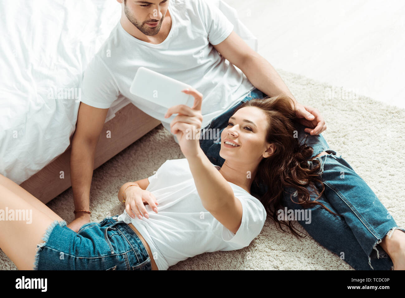 overhead view of cheerful woman taking selfie with man in bedroom Stock ...