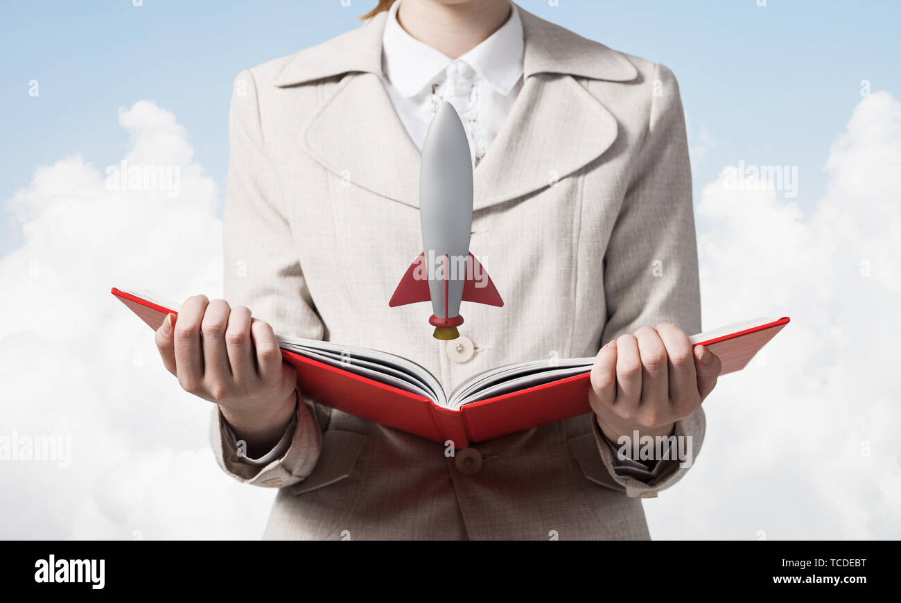 Woman showing rocket ship on open book Stock Photo - Alamy