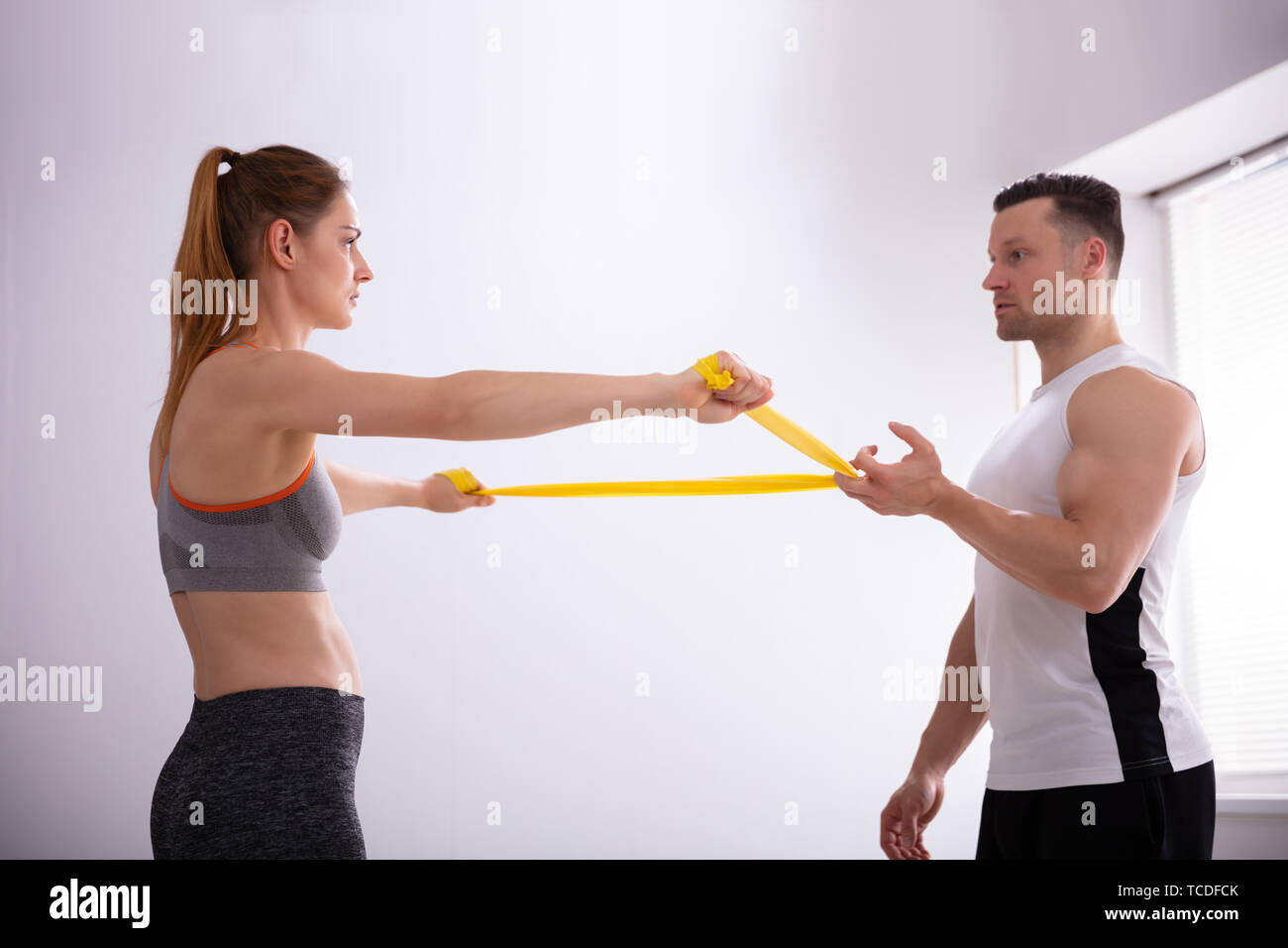 Side View Of Young Woman And Male Gym Trainer Doing Exercise With ...