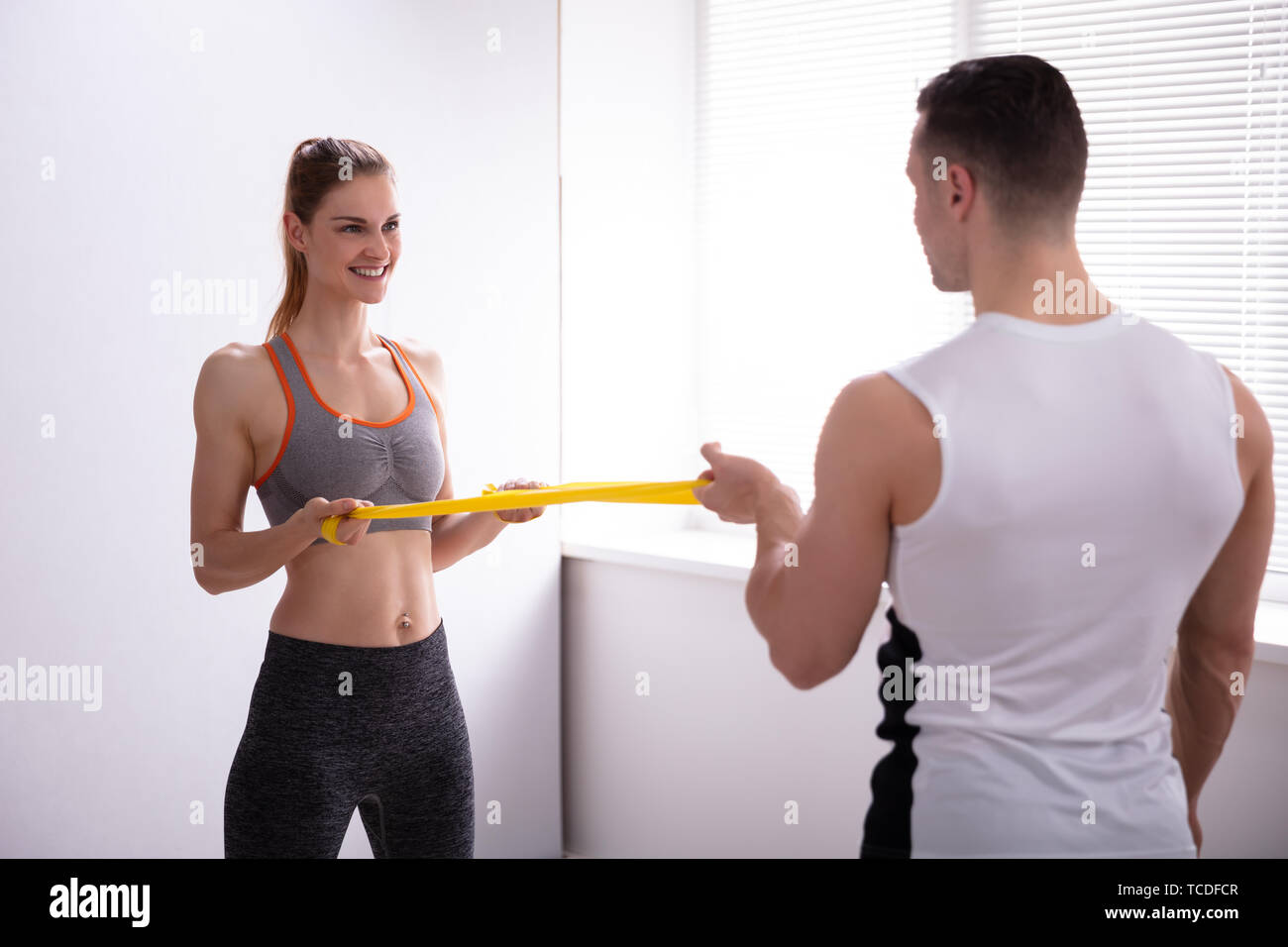 Side View Of Young Woman And Male Gym Trainer Doing Exercise With ...