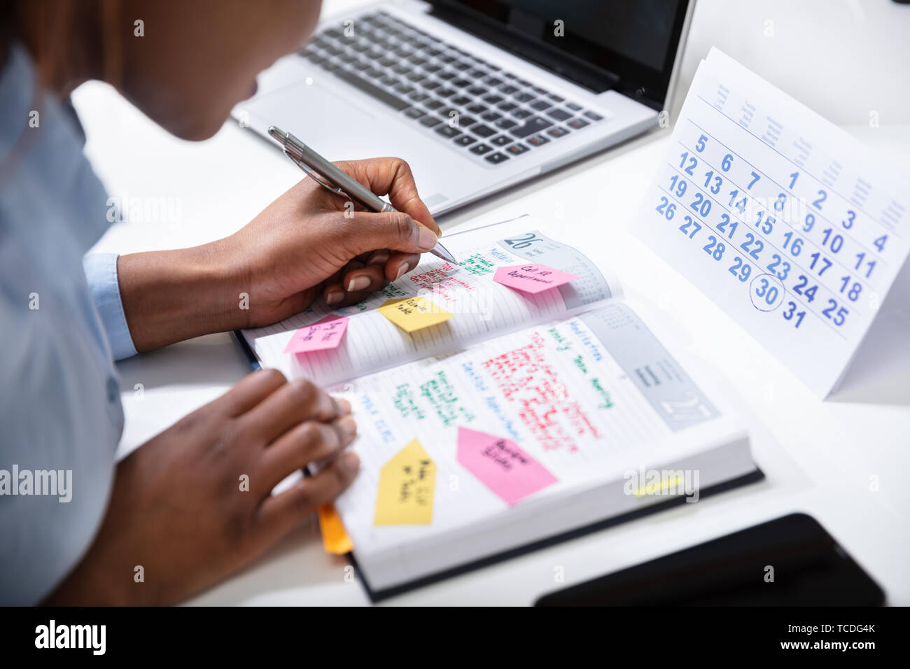 Businesswoman's Hand Checking Schedule In Diary With Calendar On White ...