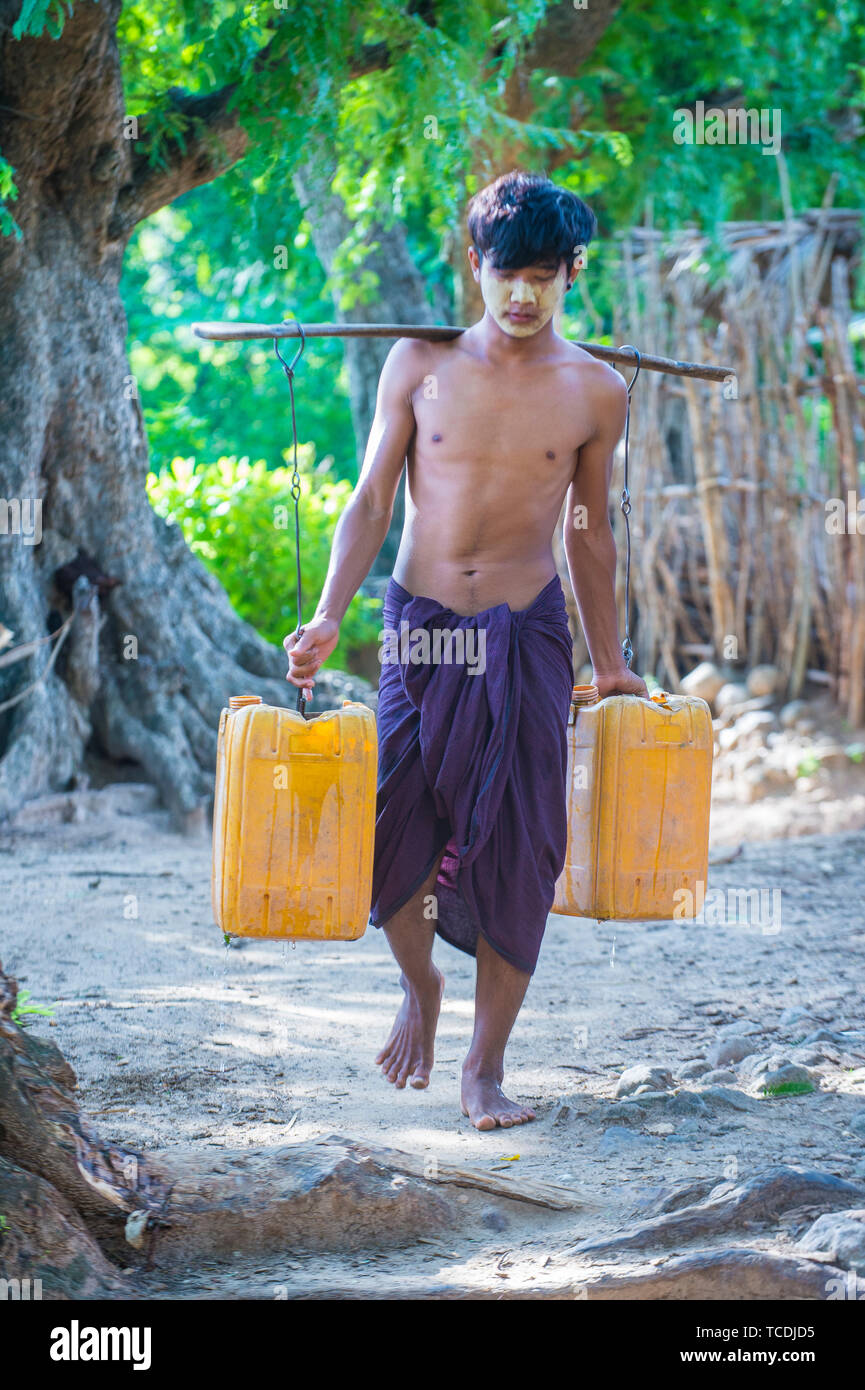 Burmese Farmer carrying plastic buckets filled with water in a village ...