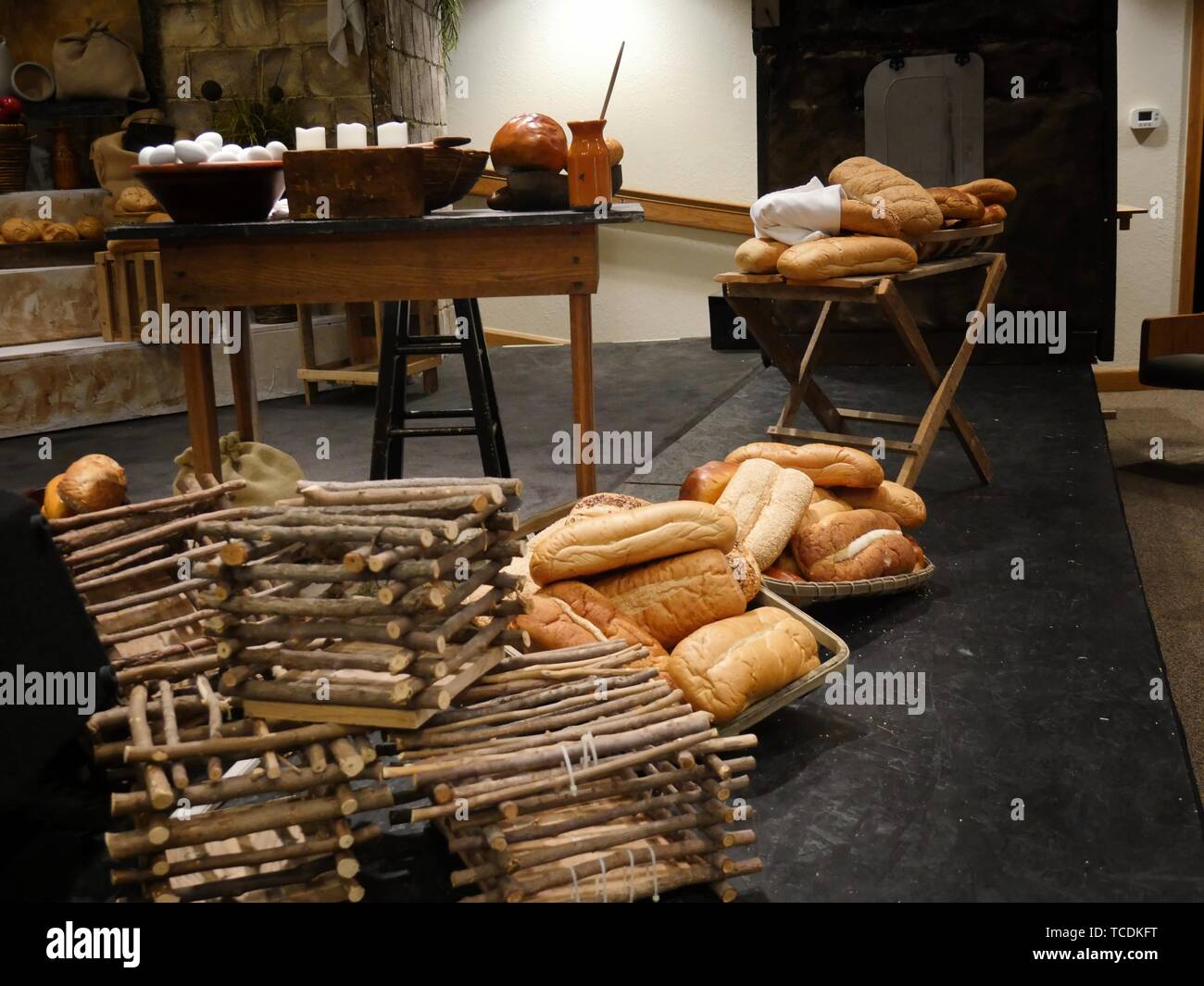 Kitchen stage set with loaves of bread, pile of wood kindling used for ...