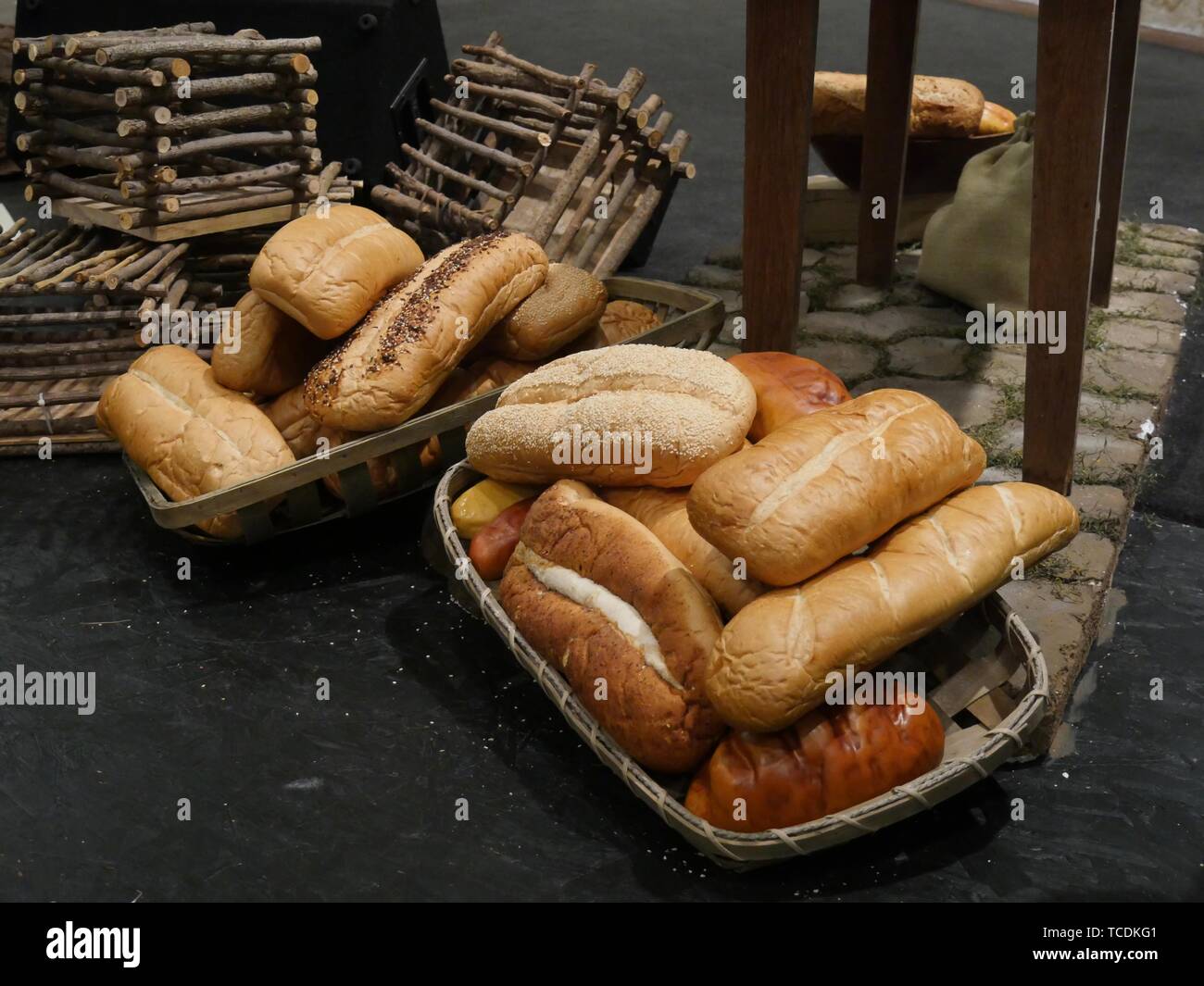 Assorted loaves of bread in wicker baskets used as props in a stage set ...