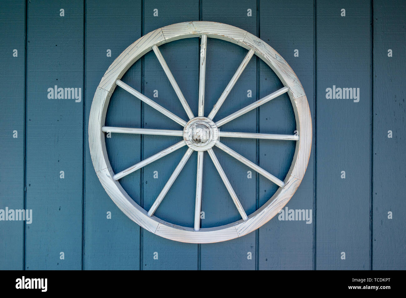 White wagon wheel hanging on blue wall Stock Photo - Alamy