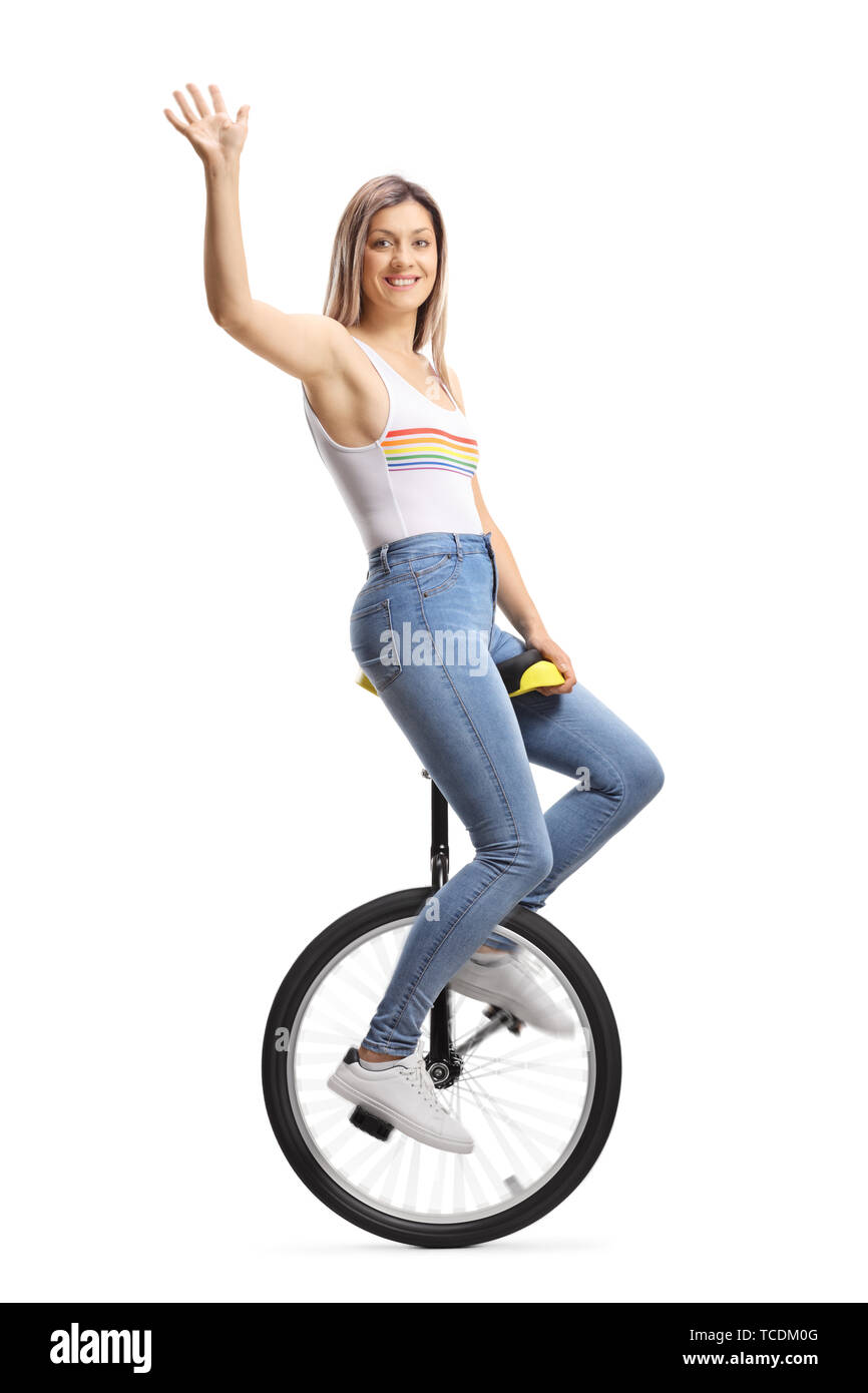 Young beautiful woman riding a unicycle and waving isolated on white ...
