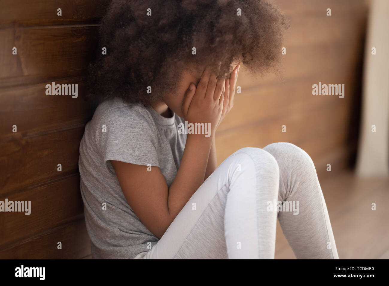 Upset african american child girl crying sitting alone on floor Stock ...