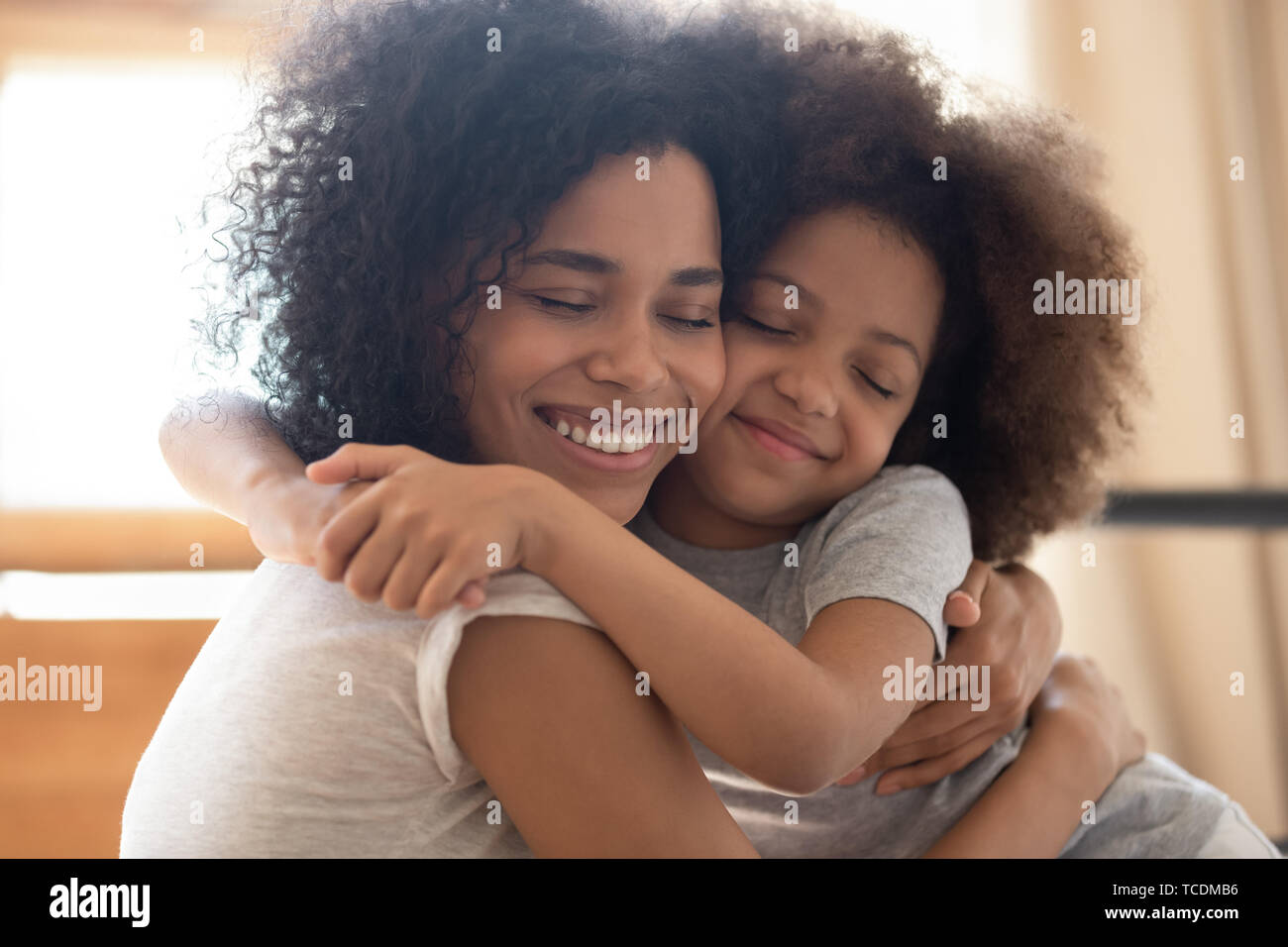 Cute affectionate african mother and little kid daughter embrace cuddle ...
