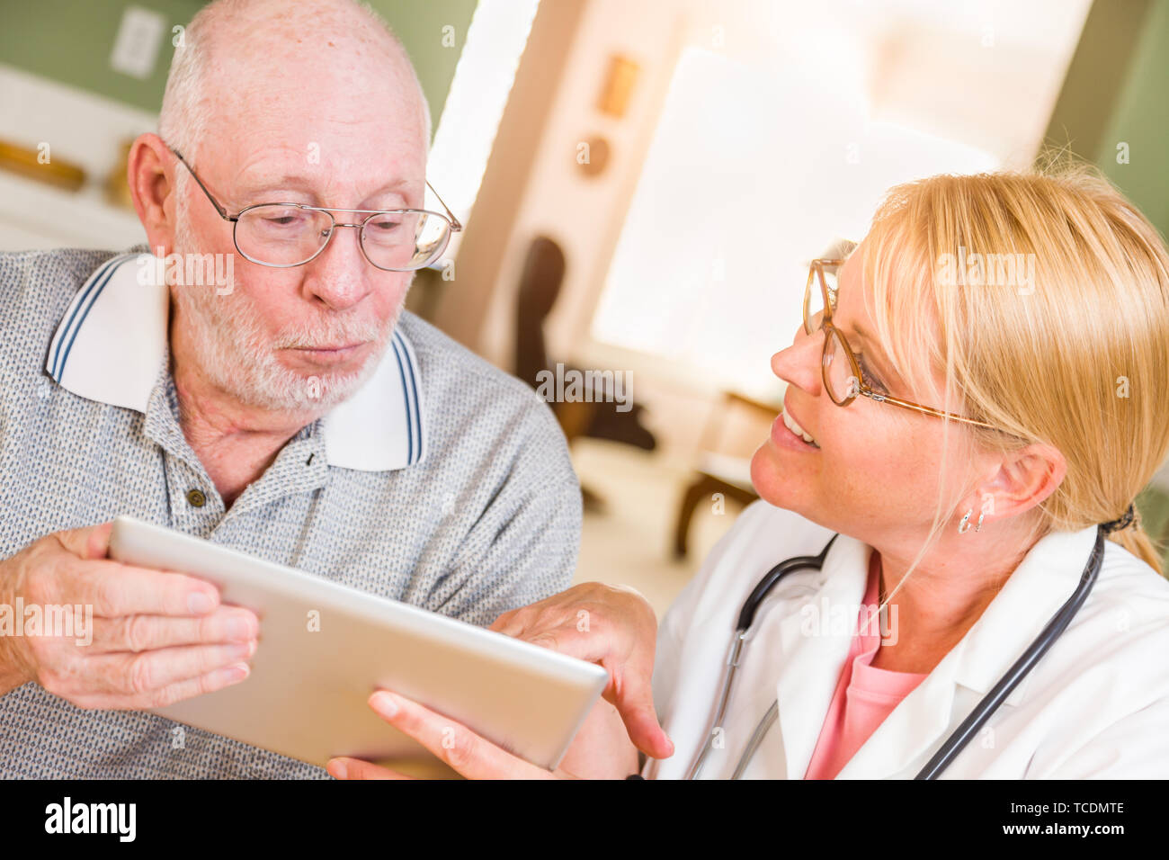 Female Doctor or Nurse Showing Senior Man Touch Pad Computer At Home ...