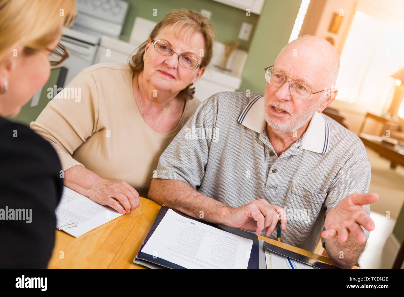 Senior Adult Couple Going Over Documents in Their Home with Agent At ...