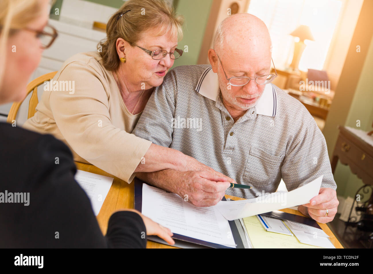 Senior Adult Couple Going Over Documents in Their Home with Agent At ...