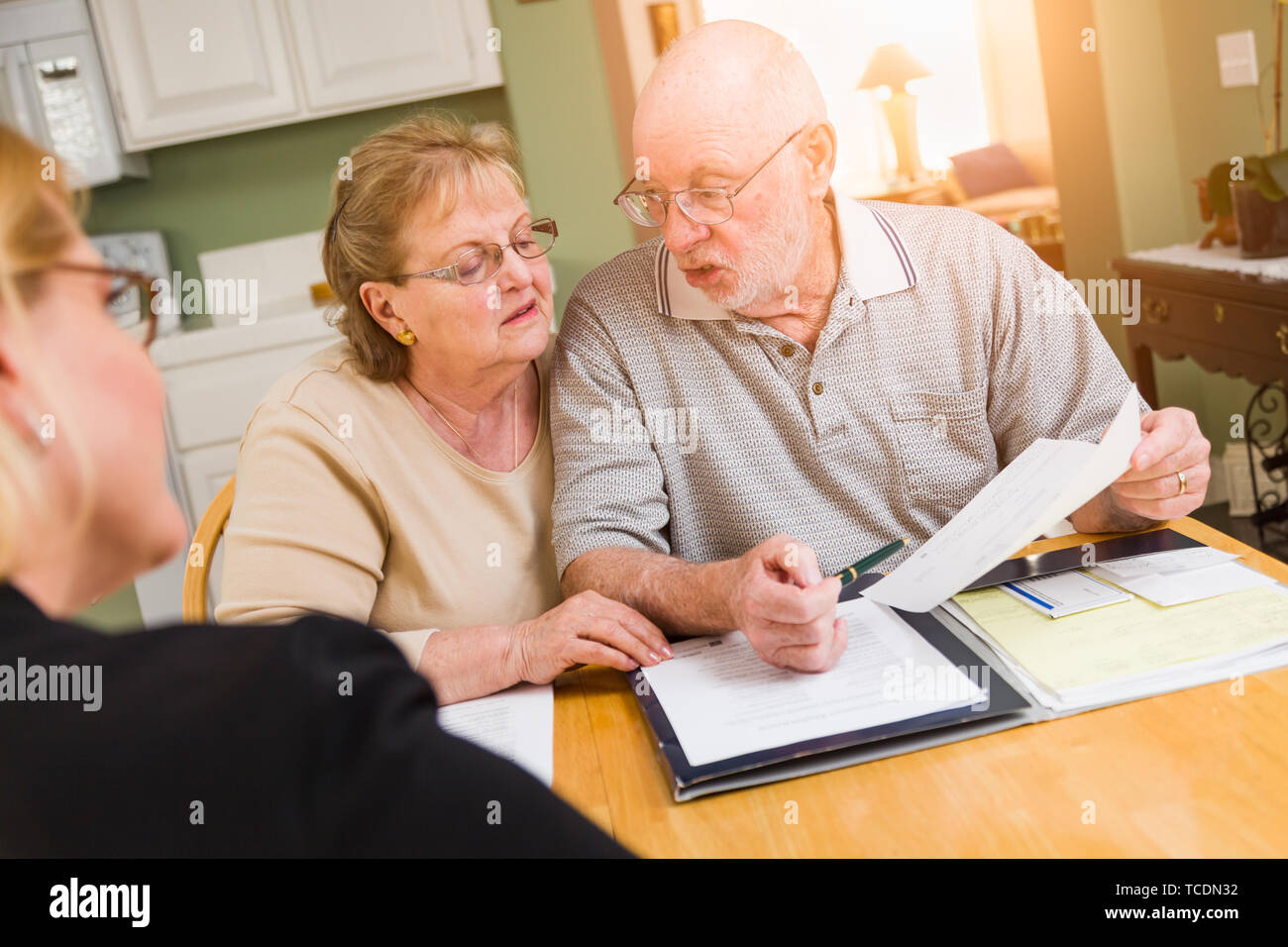 Senior Adult Couple Going Over Documents in Their Home with Agent At ...