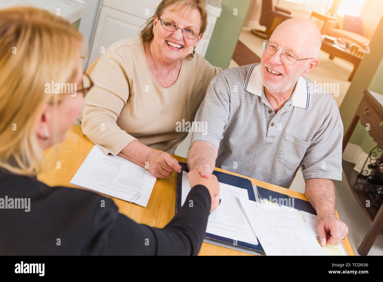 Senior Adult Couple Going Over Documents in Their Home with Agent At ...