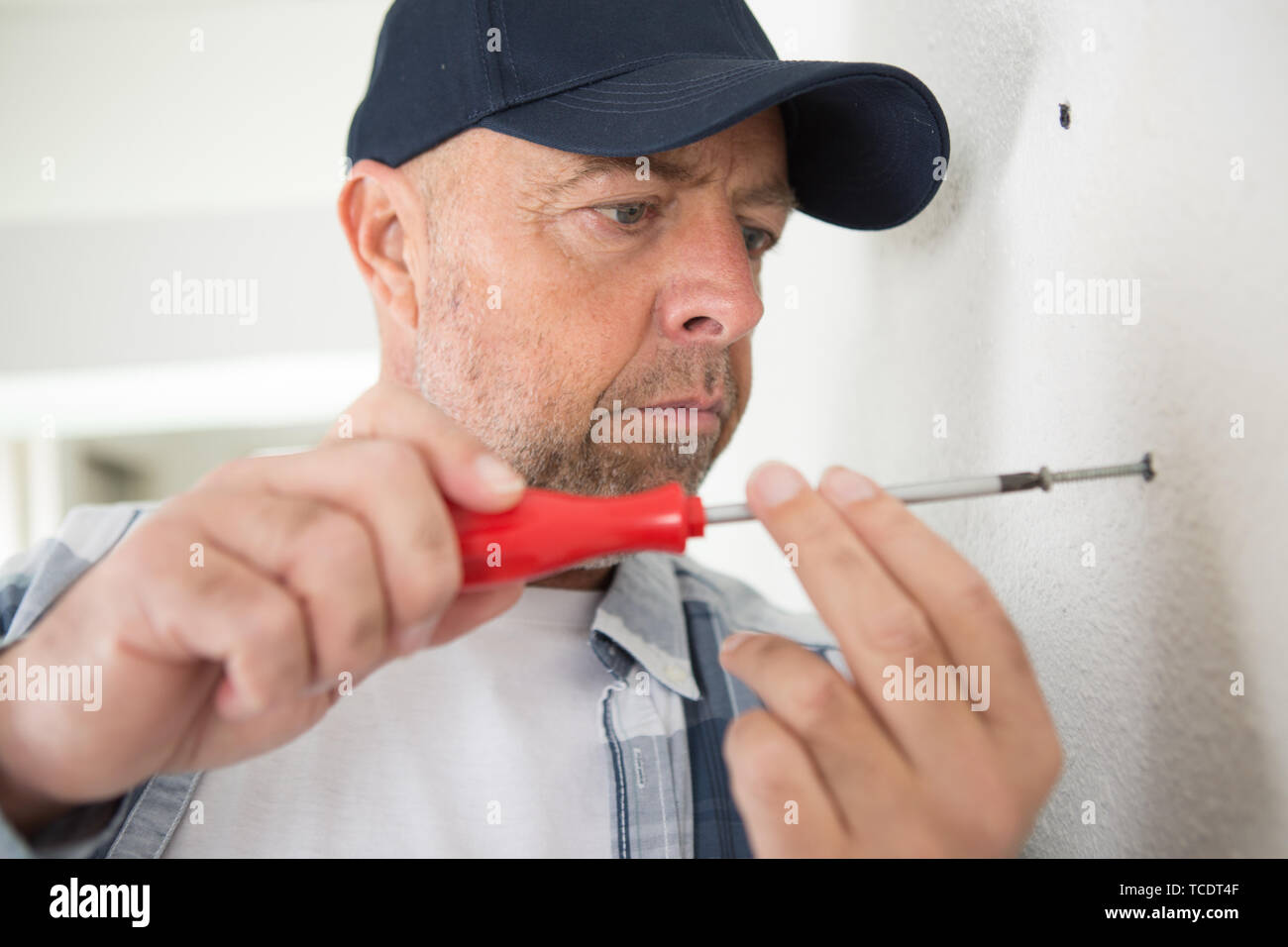 man tightens a screw on wall Stock Photo - Alamy