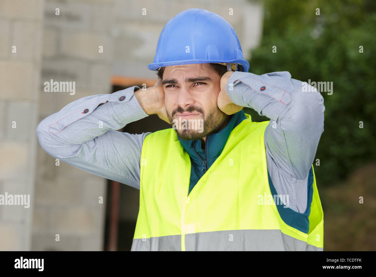 young construction worker covering ears Stock Photo - Alamy