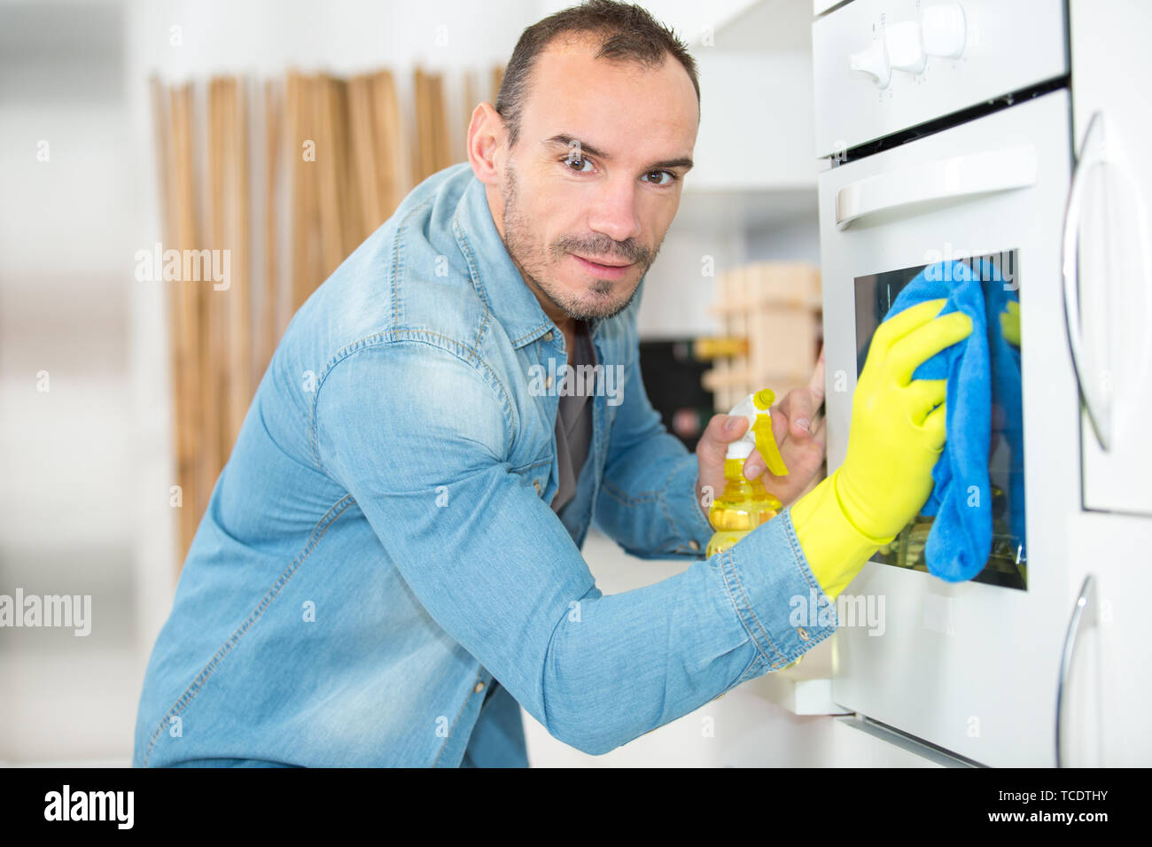 man in overall cleaning oven Stock Photo - Alamy