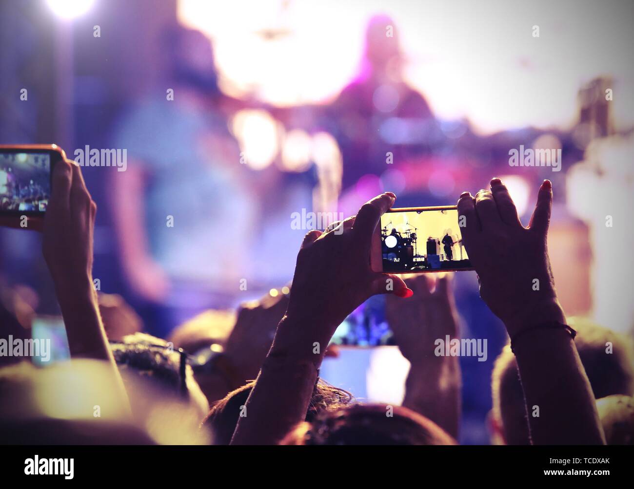 concert spectators photograph the singer who performs on stage with ...